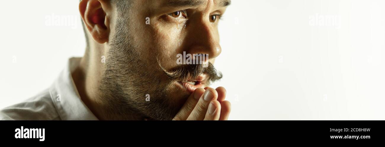 Crying, praying. Caucasian young man's close up cropped shot on studio ...