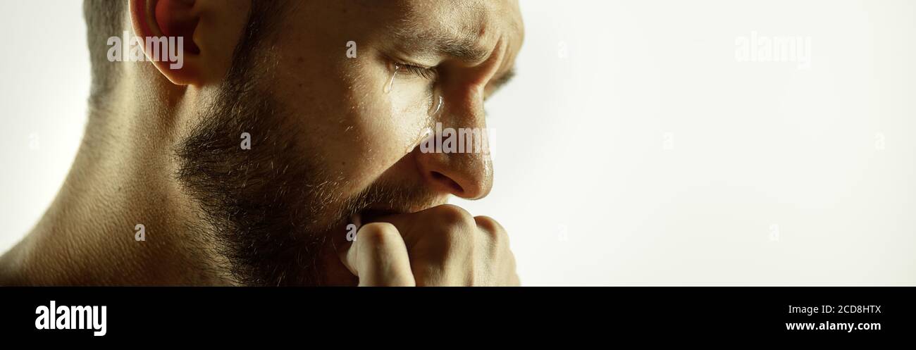 Crying. Caucasian young man's close up cropped shot on studio ...