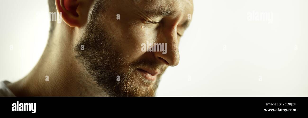 Crying. Caucasian young man's close up cropped shot on studio ...