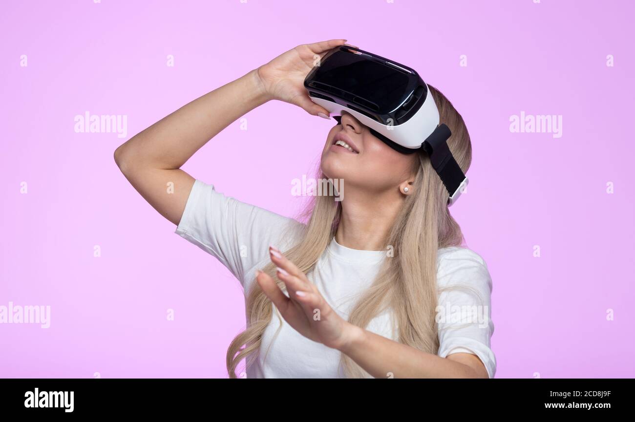 Studio portrait of happy woman using VR headset, looking up, trying to ...