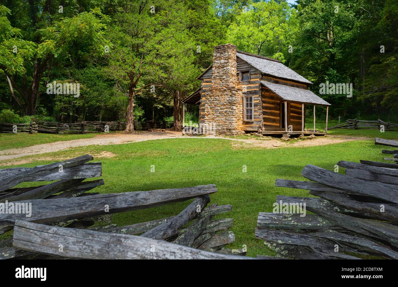 Early settler homestead with stone chimney and surronding wooden fence ...