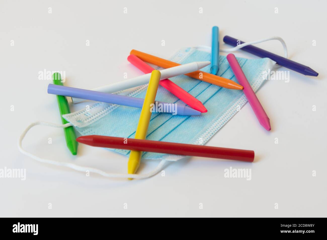 Anti virus mask on some colored school crayons. concept of back to ...