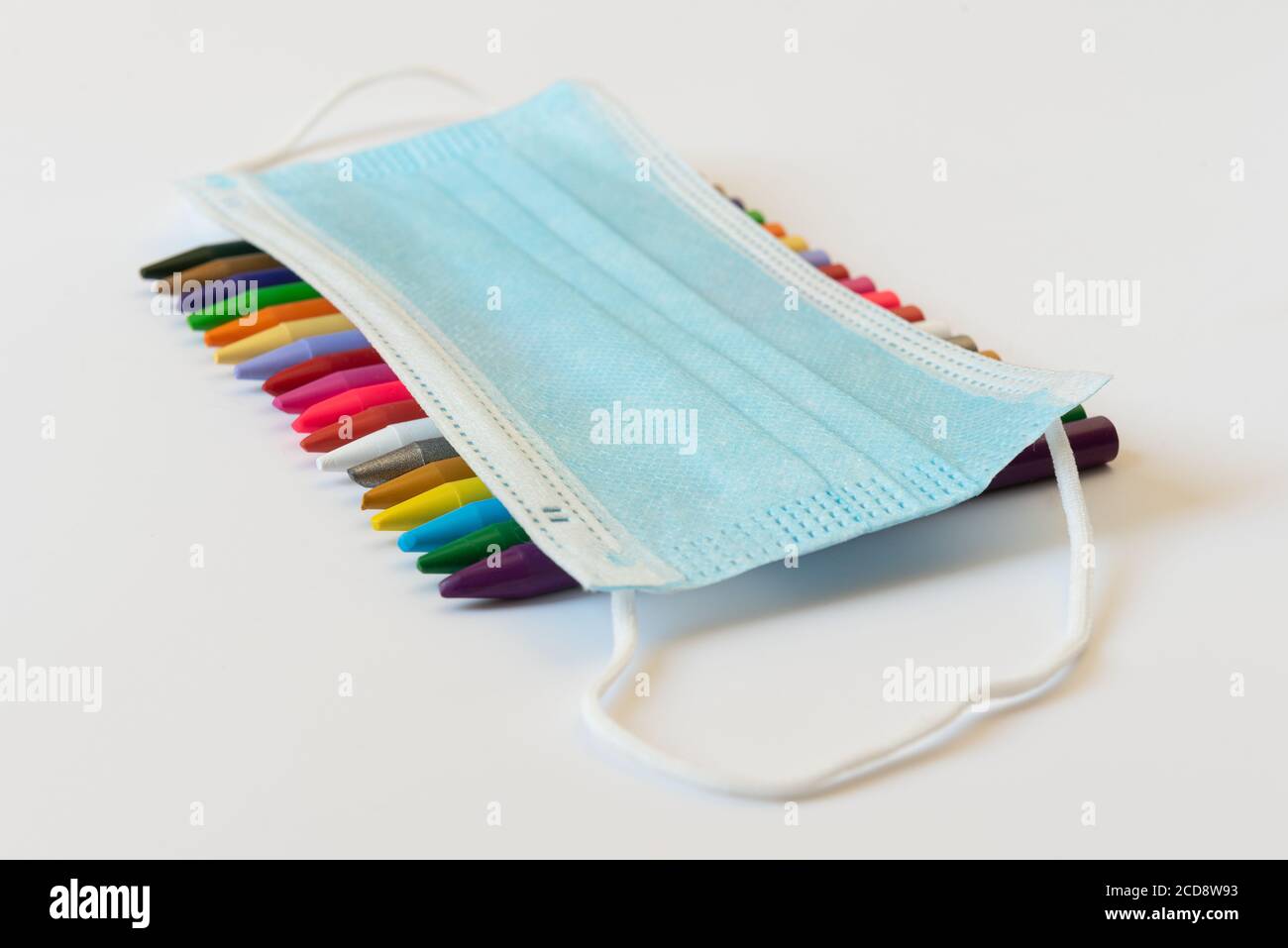 Anti virus face mask on some colored school crayons. concept of back to ...