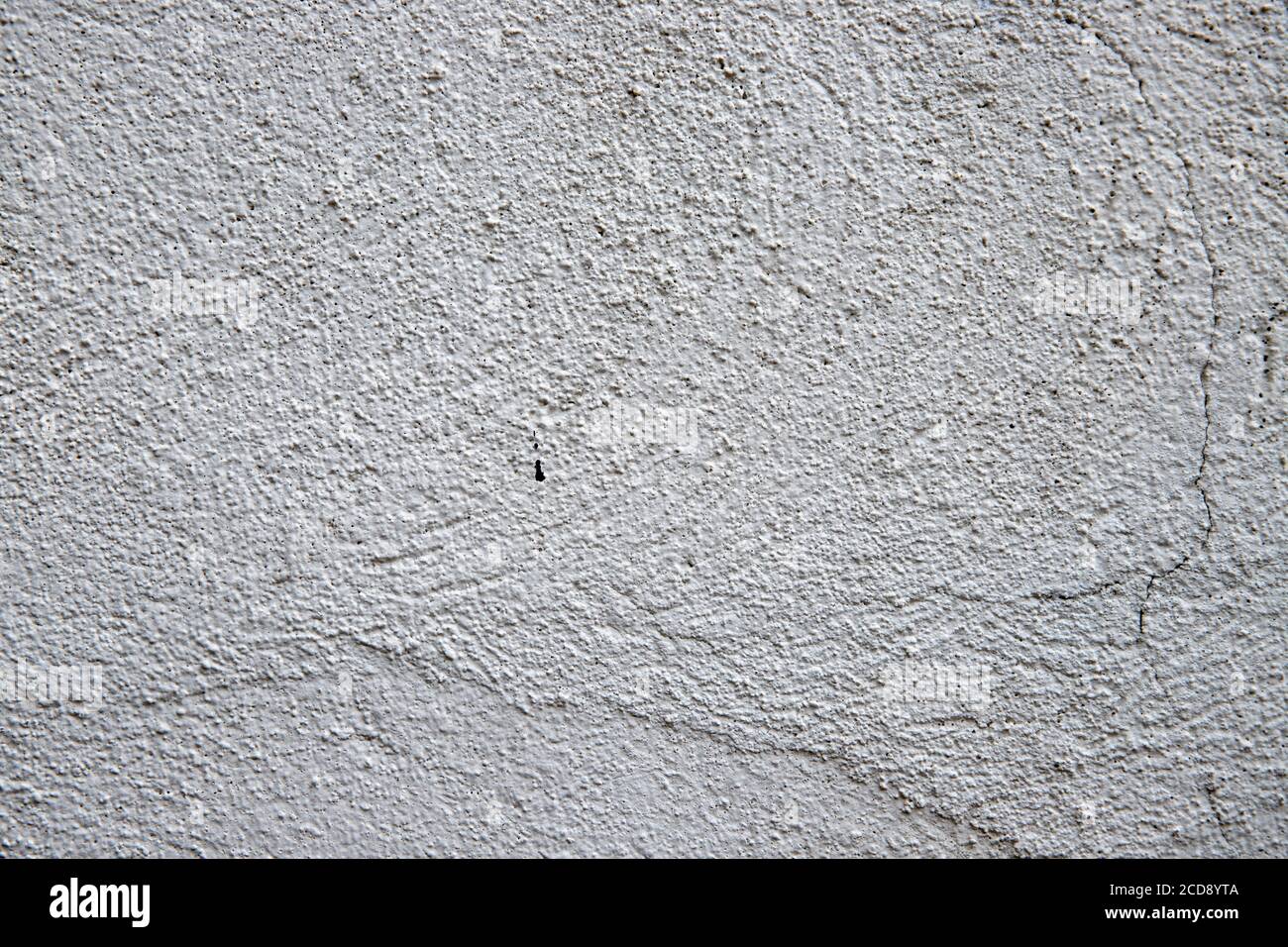 White plaster painted wall with grit and grain. Cracked wall closeup ...
