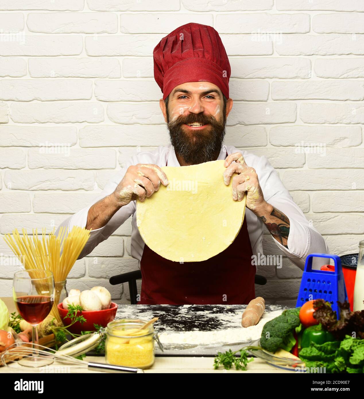 Chef makes pizza. Cook with happy face in burgundy uniform sits by ...