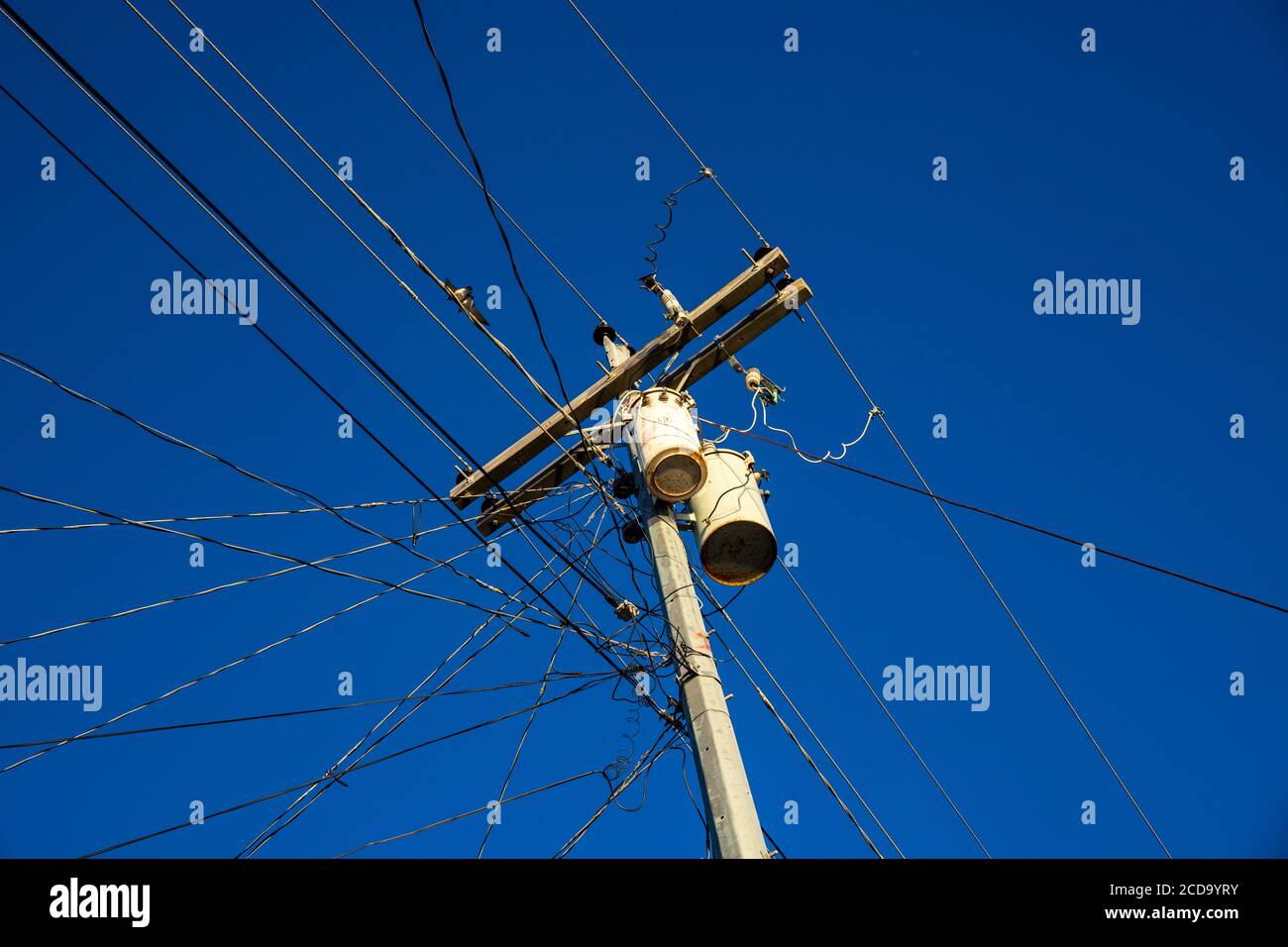 Electric wires and pillar on blue sky background. Tangle of electrical ...
