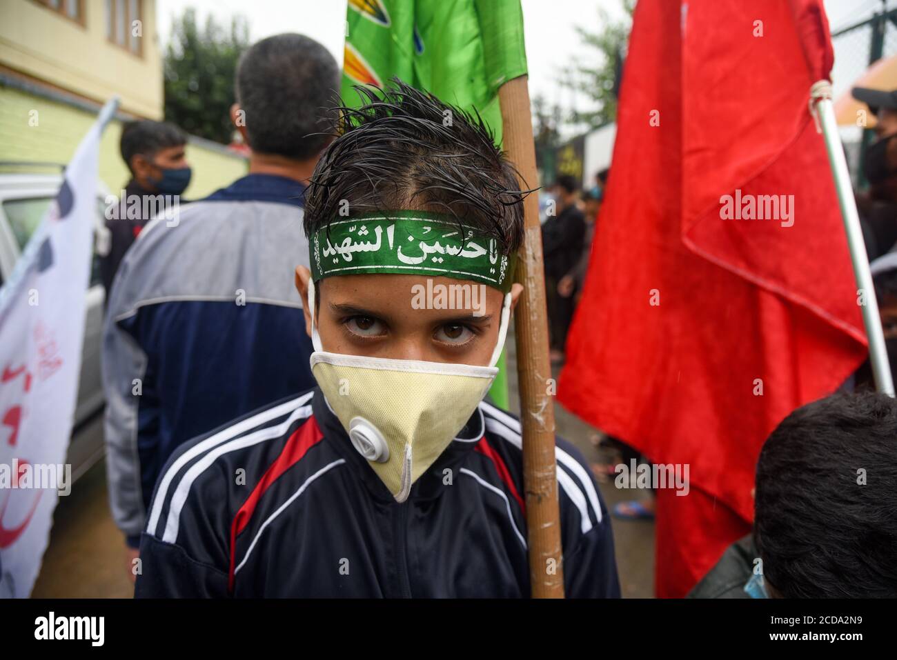 A Kashmiri shia boy wearing a face mask looks on during the Muharram ...