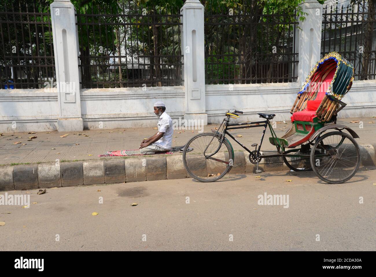 A Bangladeshi Muslim Rickshaw driver offer prayer on the street in ...