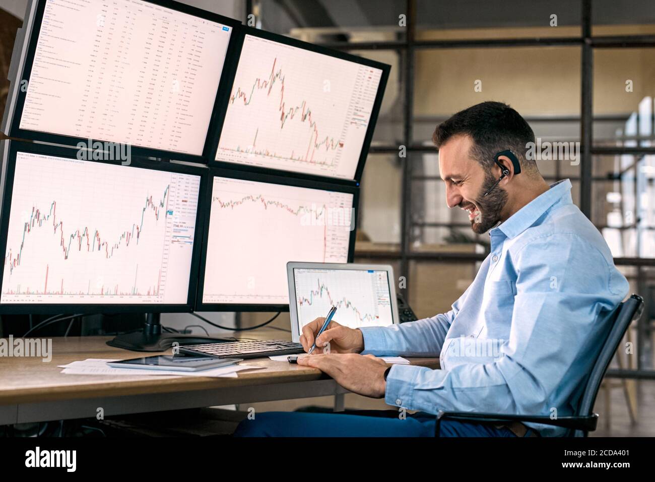 Stock Traiding. Trader wearing headset sitting at office in front of ...