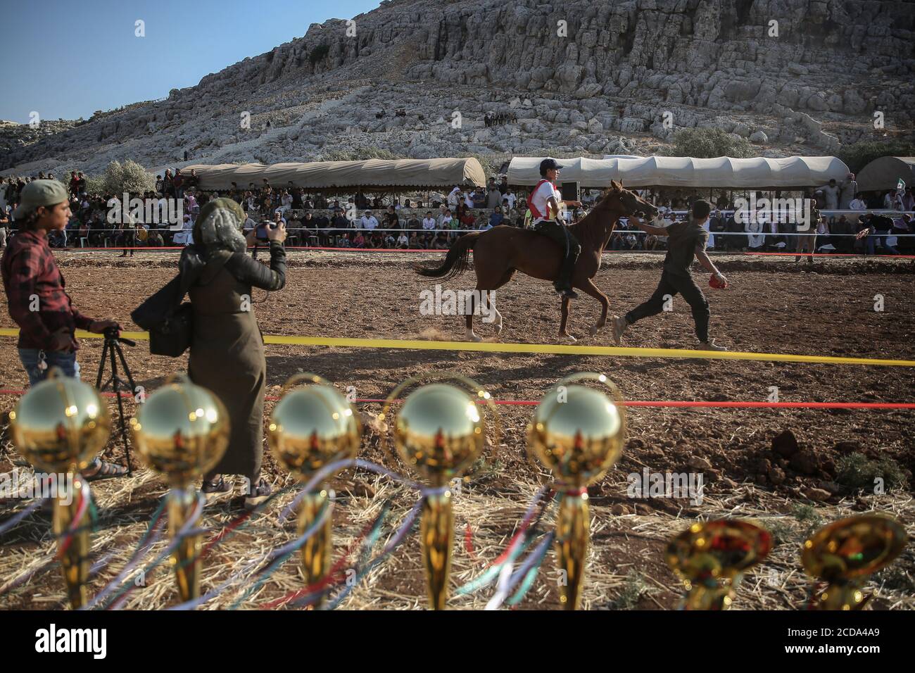 Sarmada, Syria. 27th Aug, 2020. People take pictures of a jockey riding ...
