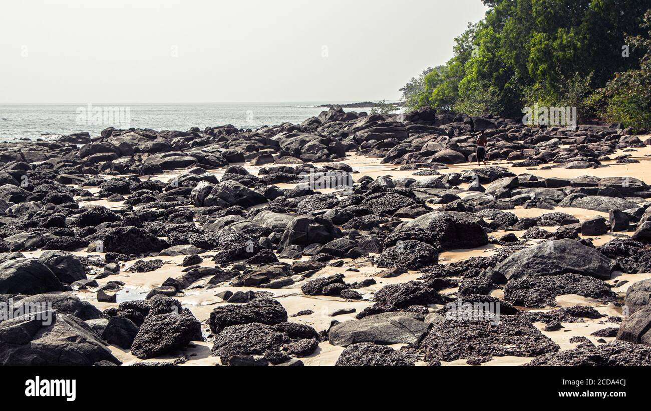 Black rocks spread out on the beach Stock Photo - Alamy