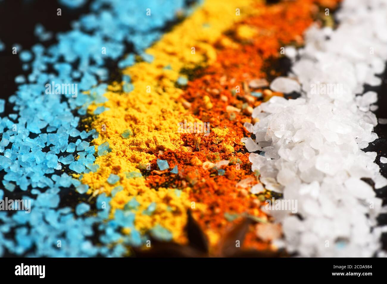 Set of spices on dark grey wood background. Lines of orange, blue ...