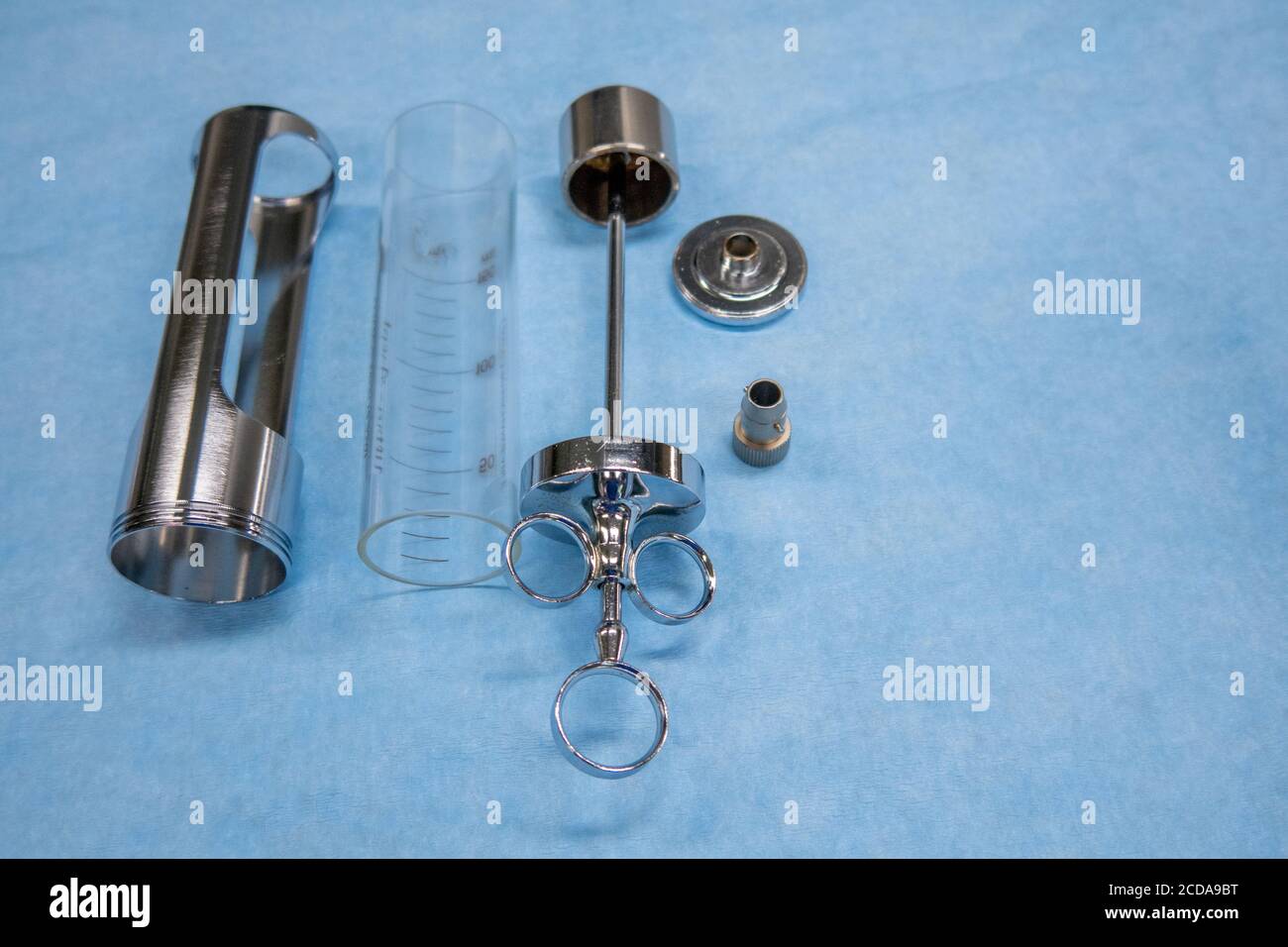 A disassembled urological bladder syringe lies on a blue OP base Stock ...