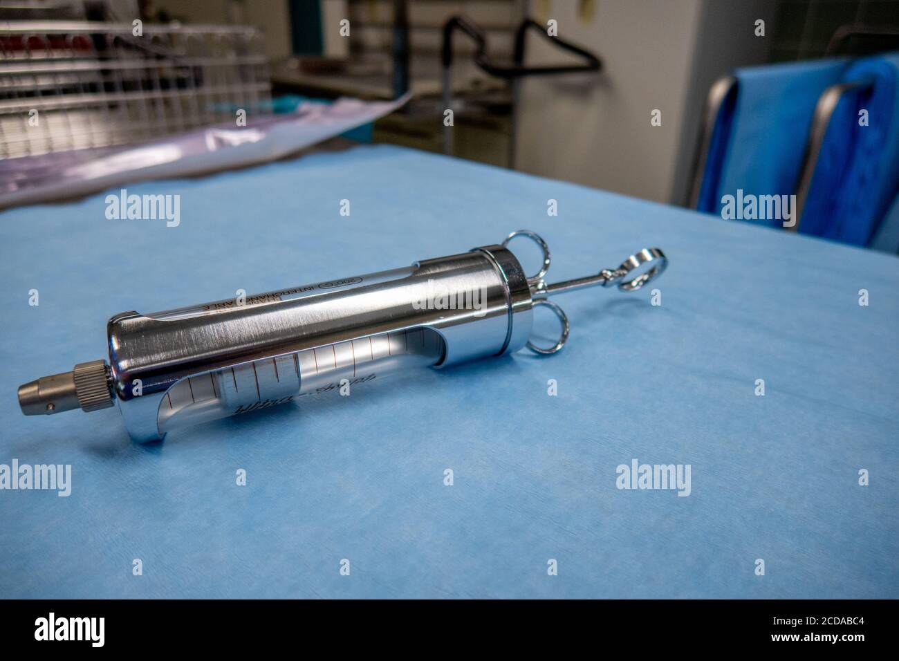 an assembled urological bladder syringe lies on a blue surgical base ...