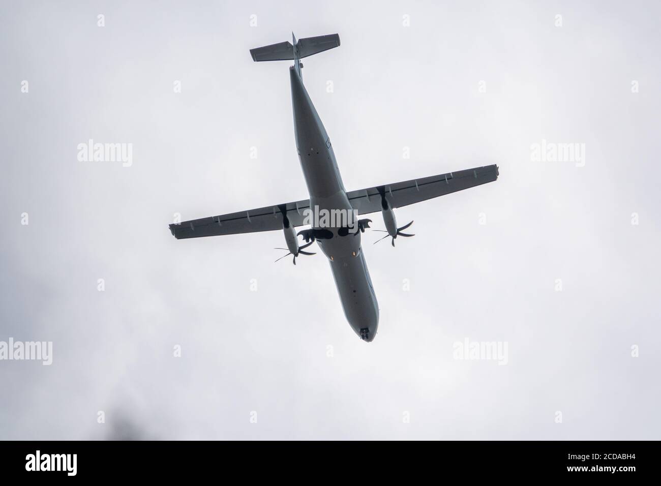 a large propeller plane with extended landing gear flies in the sky ...