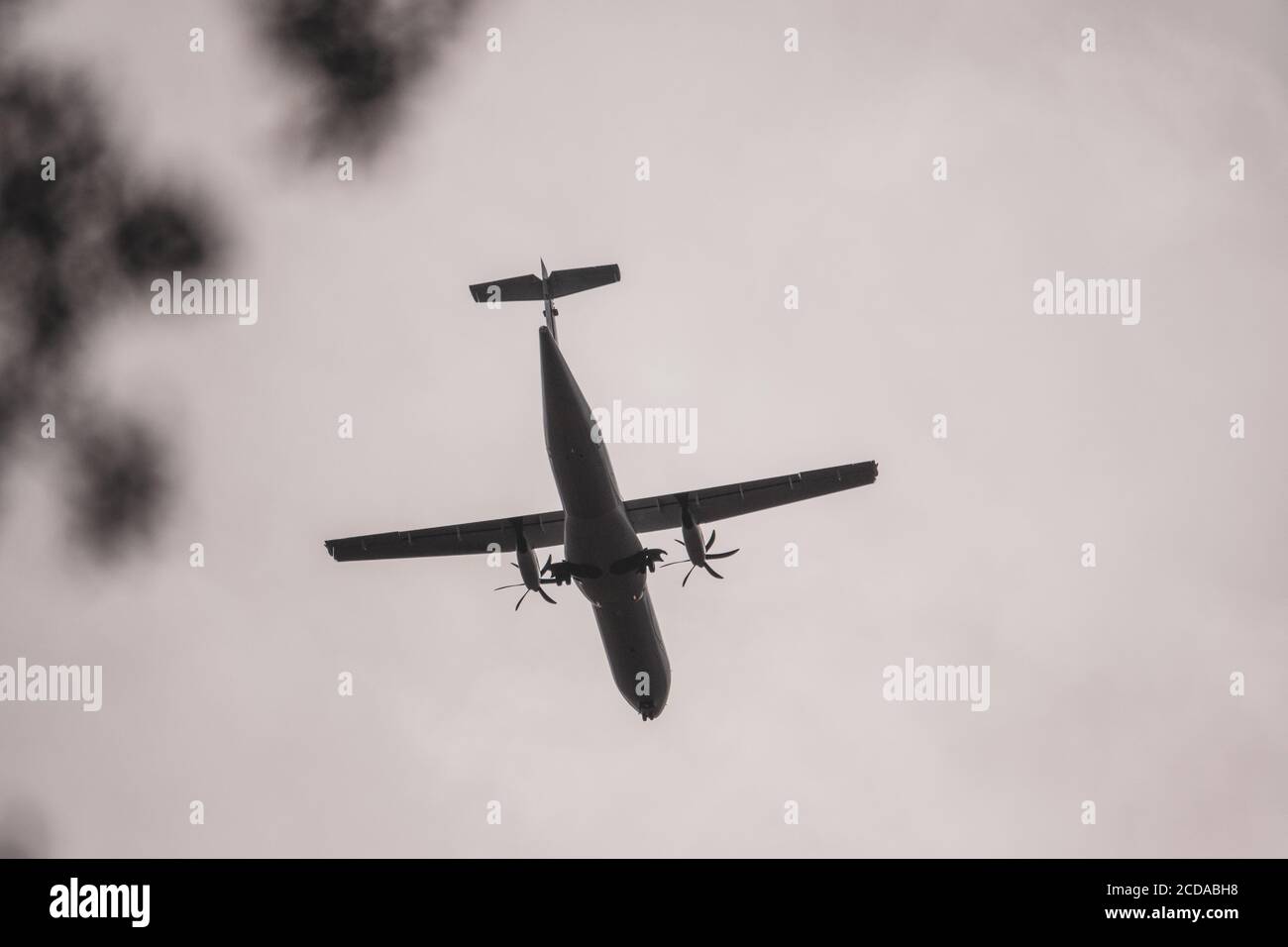 a large propeller plane with extended landing gear flies in the sky ...