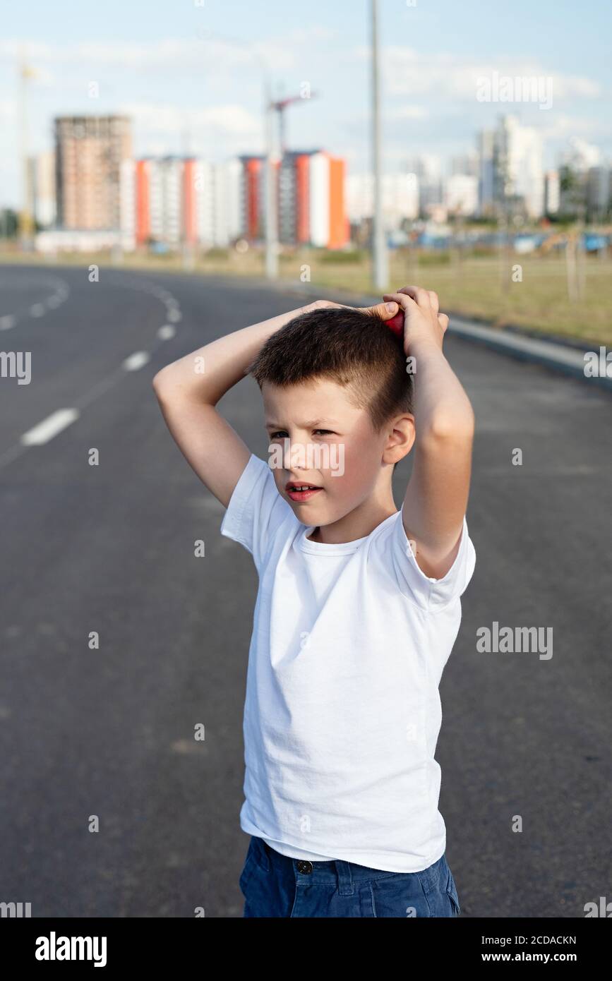 handsome boy of European appearance holds his hands behind his head ...