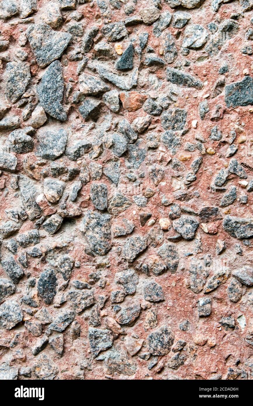 Red concrete wall facing by small black rocks. Texture pattern Stock ...