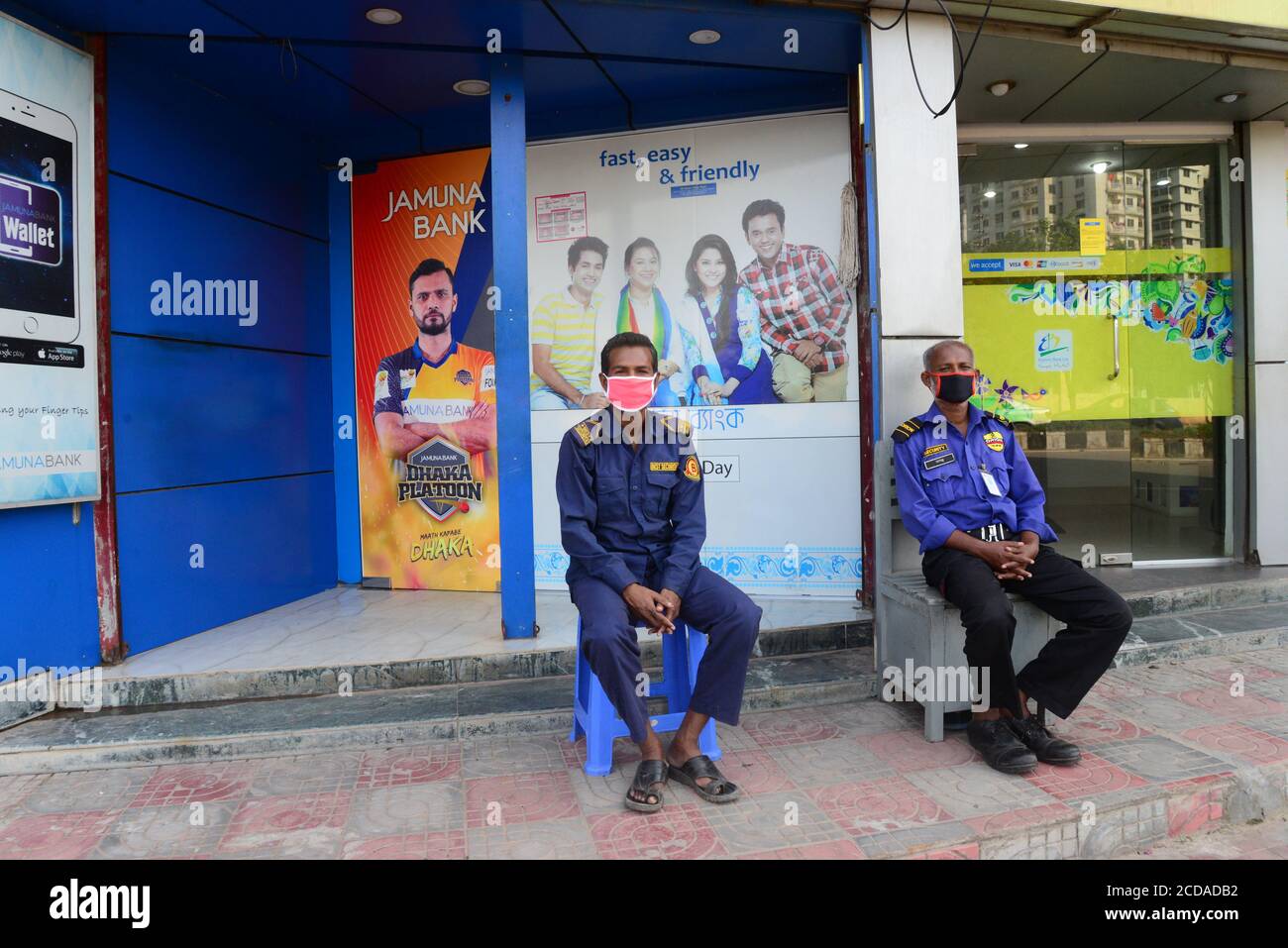 Private security guard at an ATM booth wearing a facemask as a ...