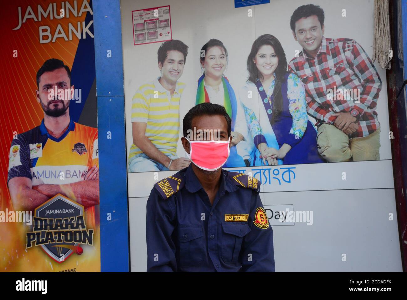 A Private security guard at an ATM booth wearing a facemask as a ...