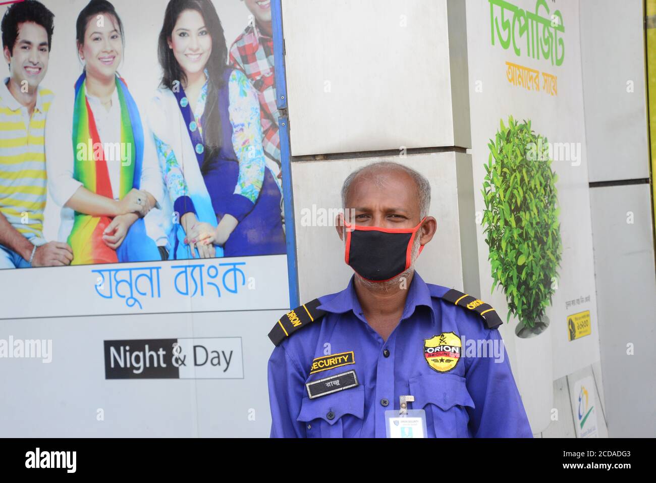 A Private security guard at an ATM booth wearing a facemask as a ...