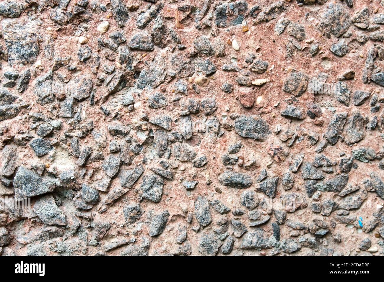 Red concrete wall covered by small black rocks Stock Photo - Alamy