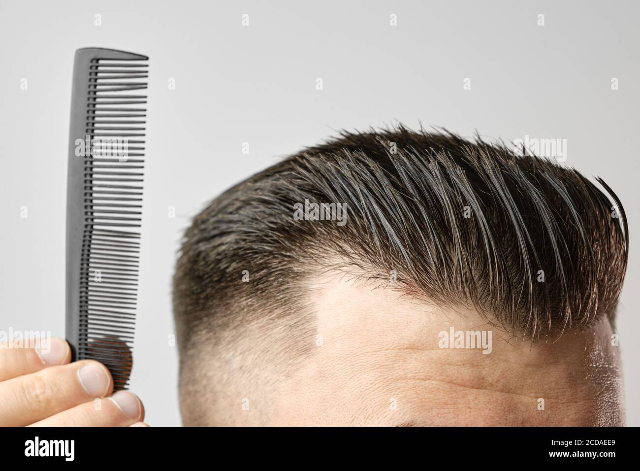 Close up young man combing his hair with a plastic comb. Styling hair ...