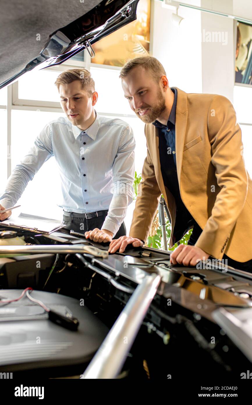 young caucasian cars salesman show the perfect assemble hood of car in ...
