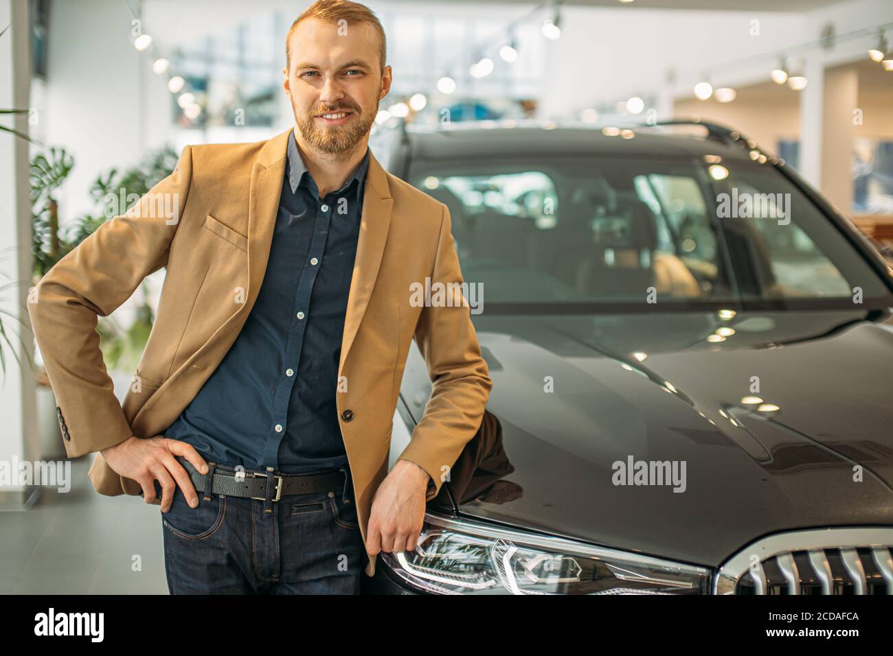handsome young caucasian man buy a new car in dealership. happy owner ...