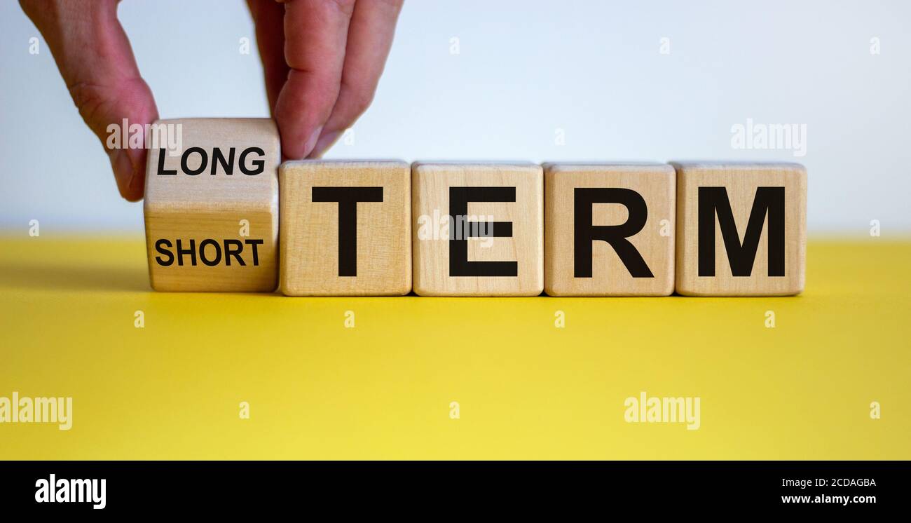Hand turns a cubes and changes the expression 'SHORT TERM' to 'LONG ...