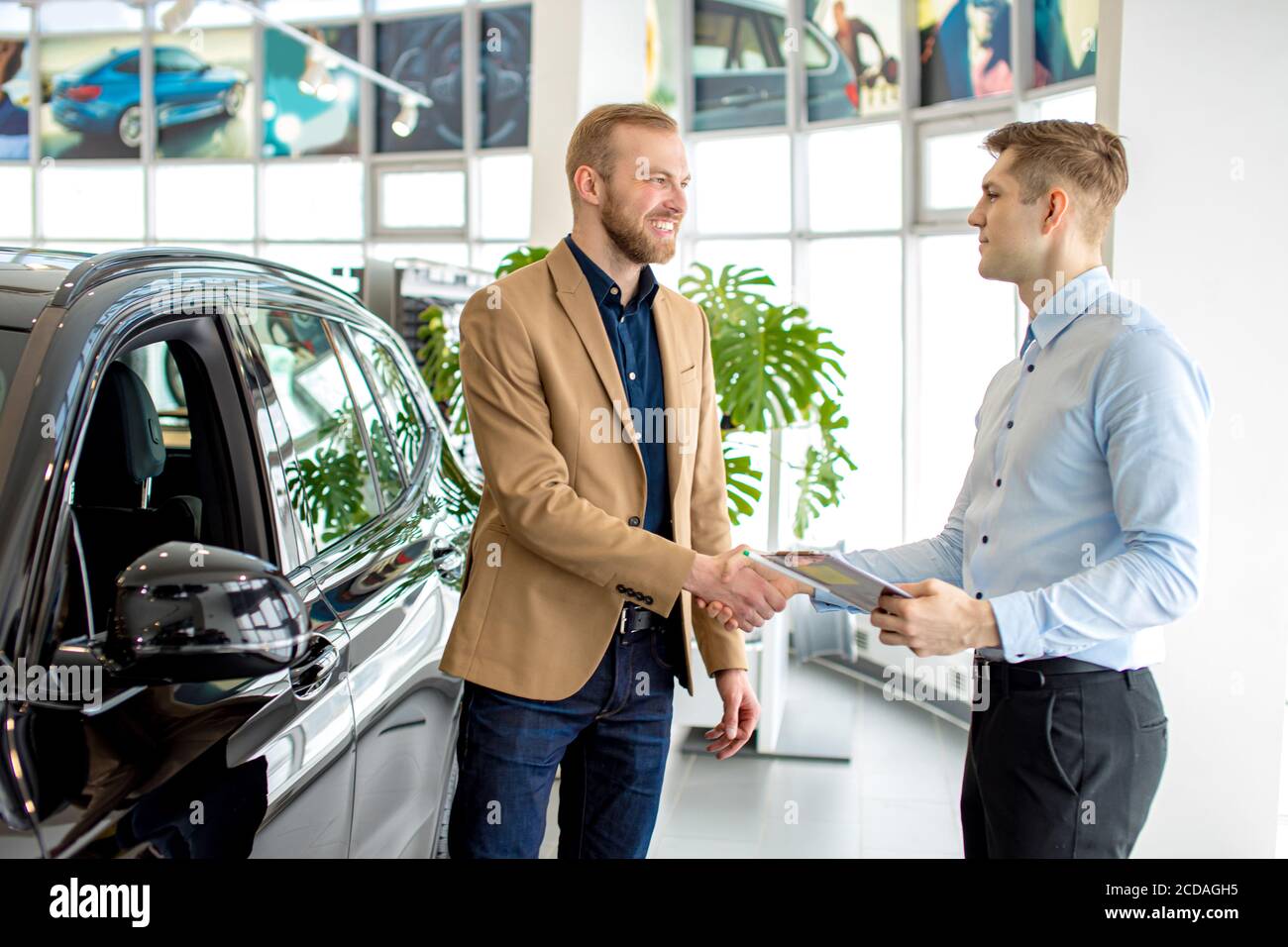 happy caucasian man owner of new car, stand in dealership shake hand to ...