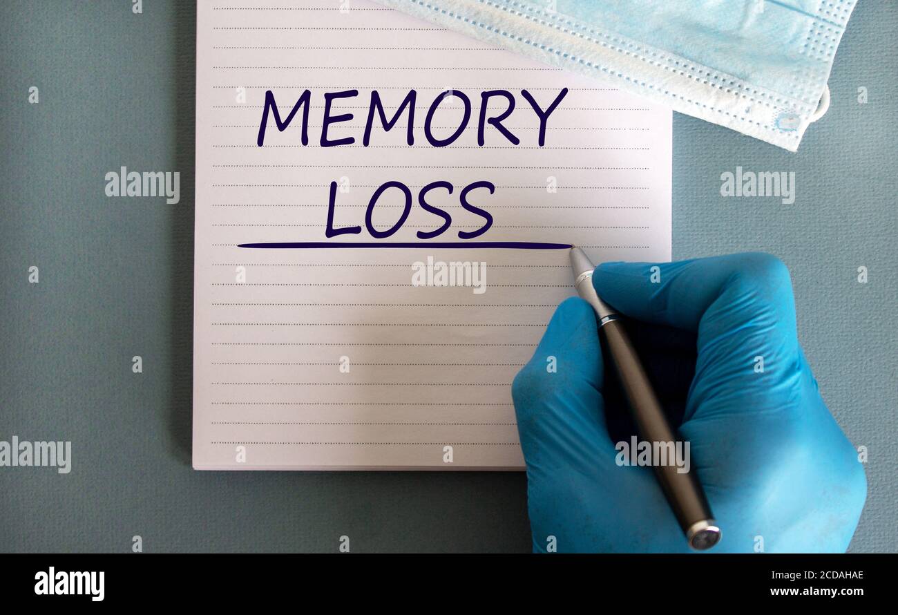 Male doctors hand in blue glove writes 'memory loss' on a white note ...