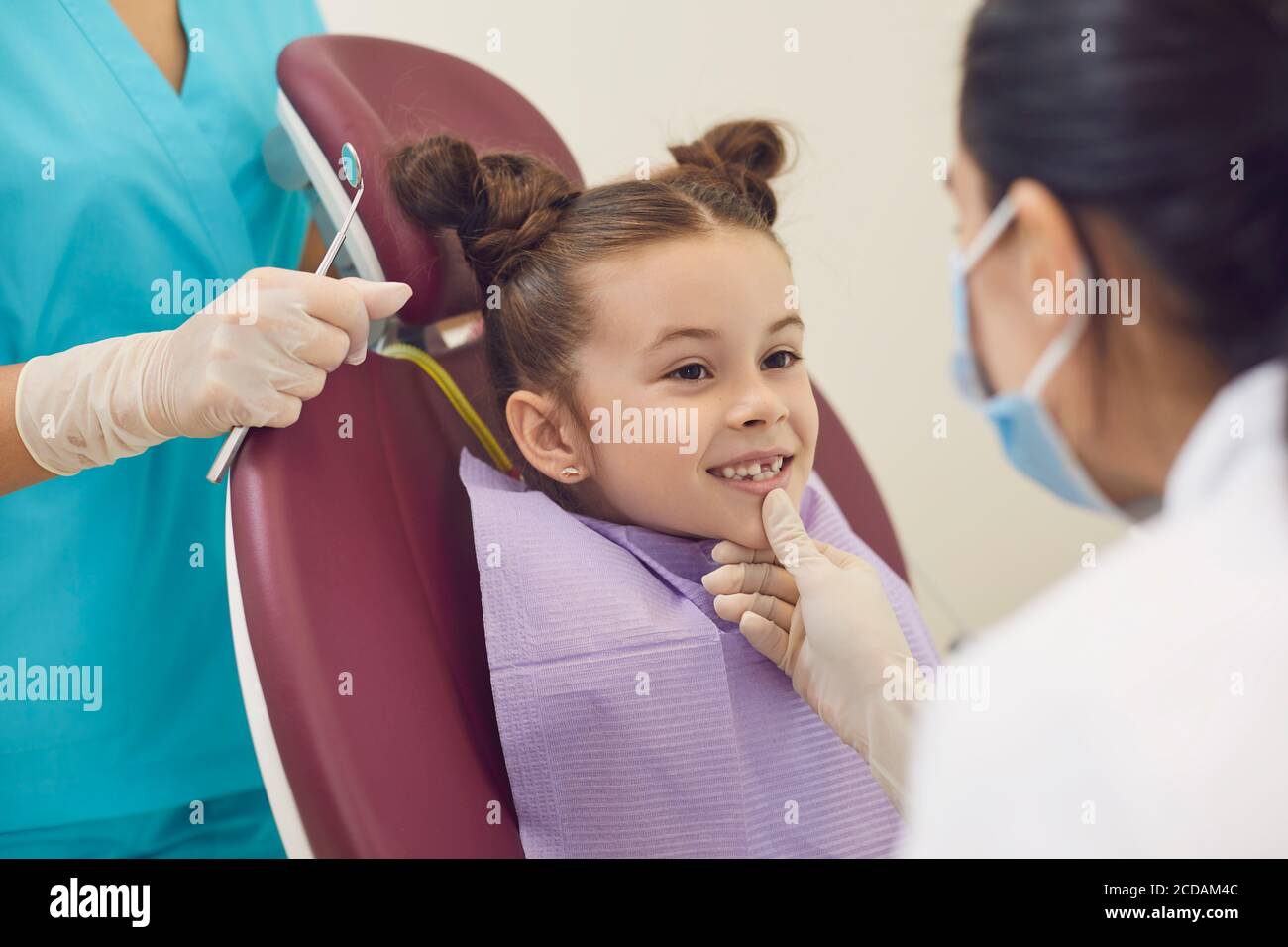 Woman dentist and assistant examining smiling little girl teeth in dental clinic Stock Photo - Alamy