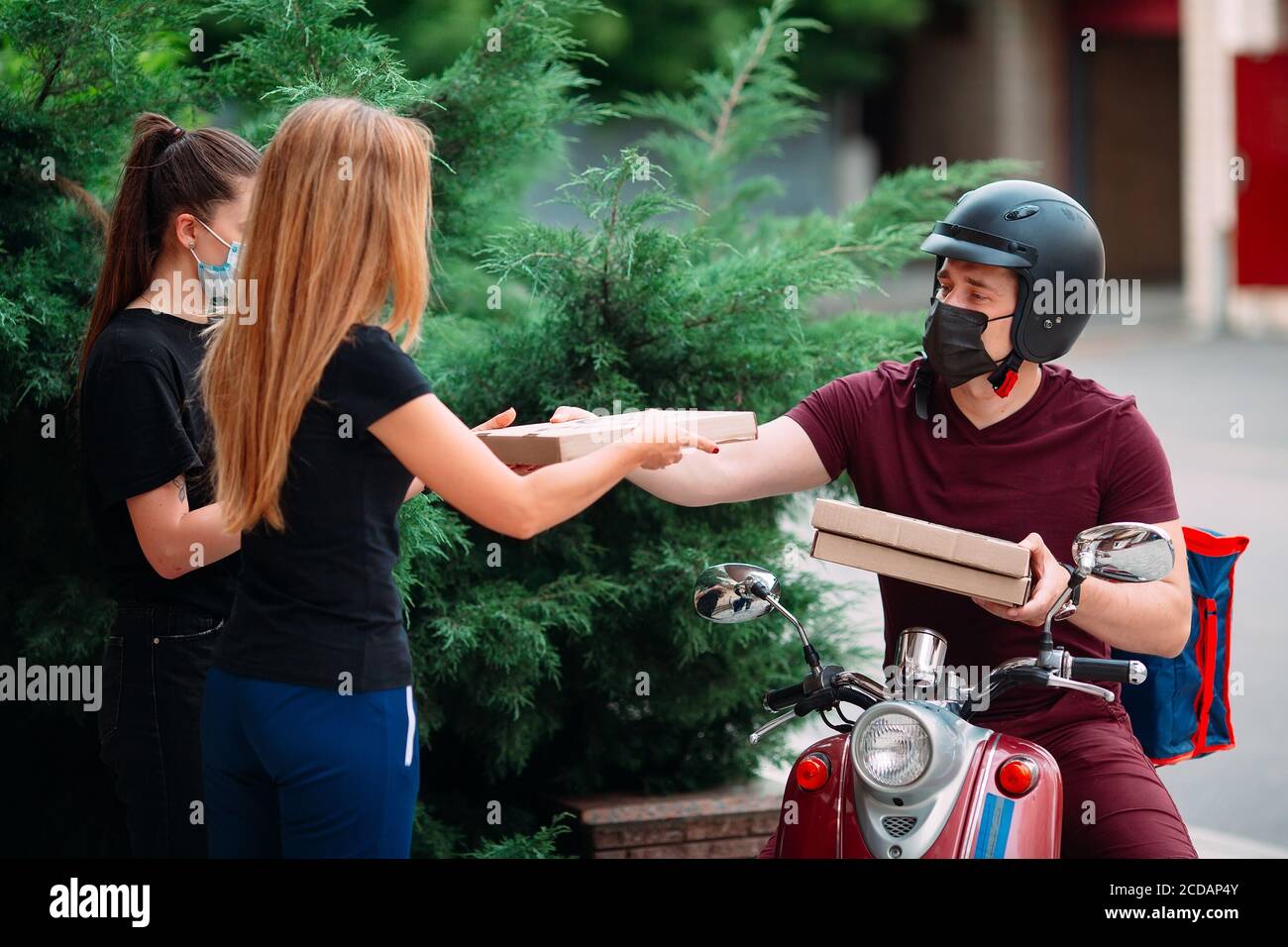 Two womans pick up delivery food box from delivery rider with scooter ...