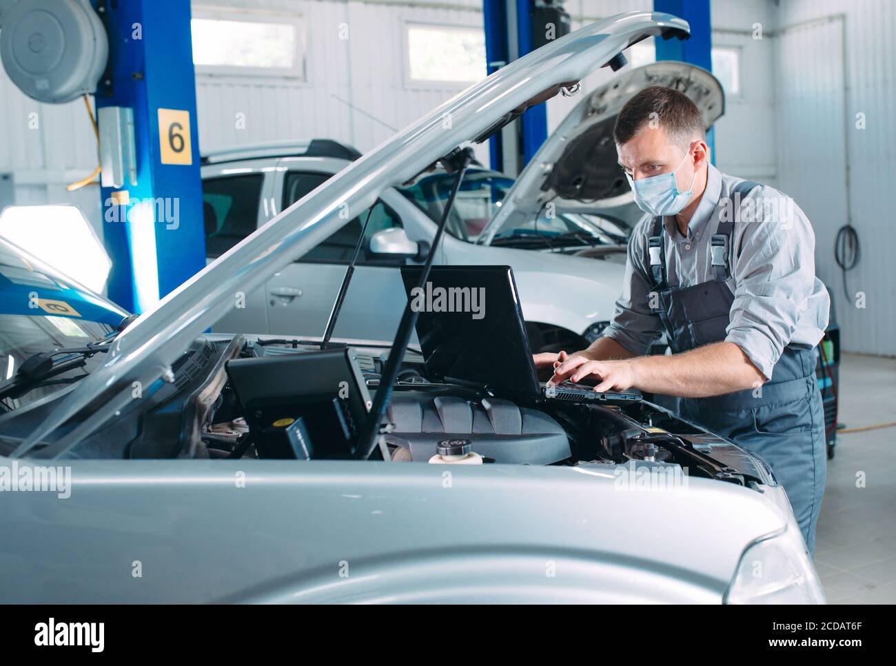 Mechanic in uniform and protective mask work in a car workshop Stock ...