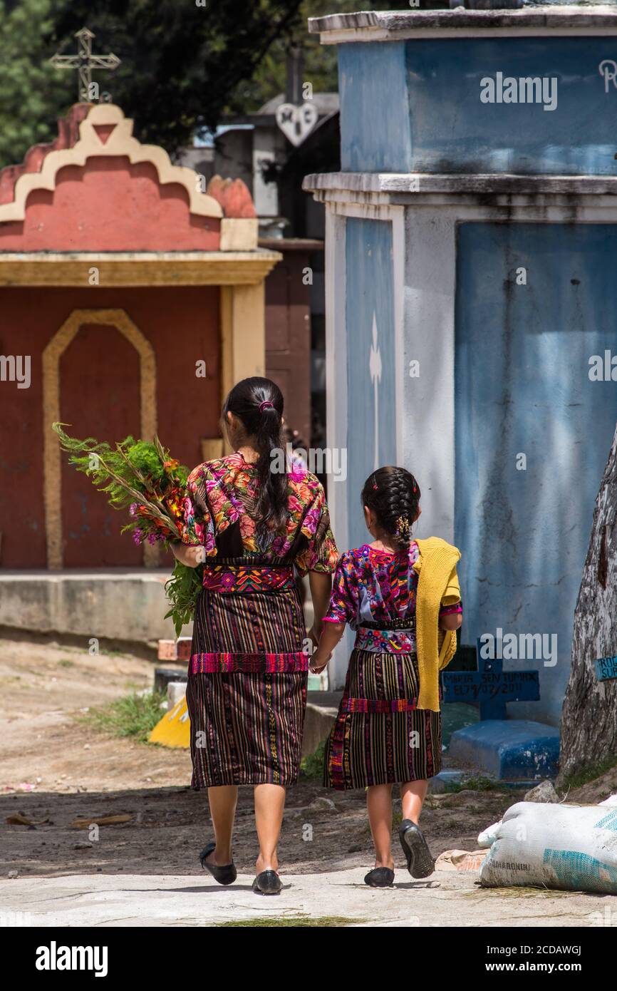 A Quiche Mayan mother and daughter in traditional dress bring flowers ...