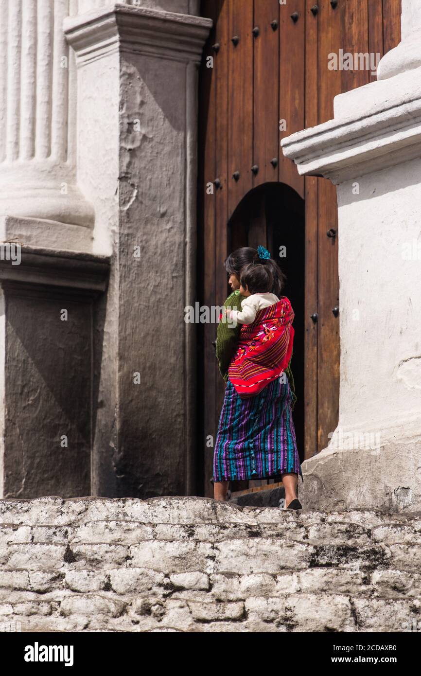 A young Quiche Mayan woman, in traditional dress, and her daughter walk ...