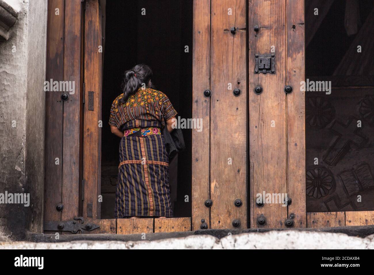 A Quiche Mayan woman in traditional dress stands in the old wooden ...