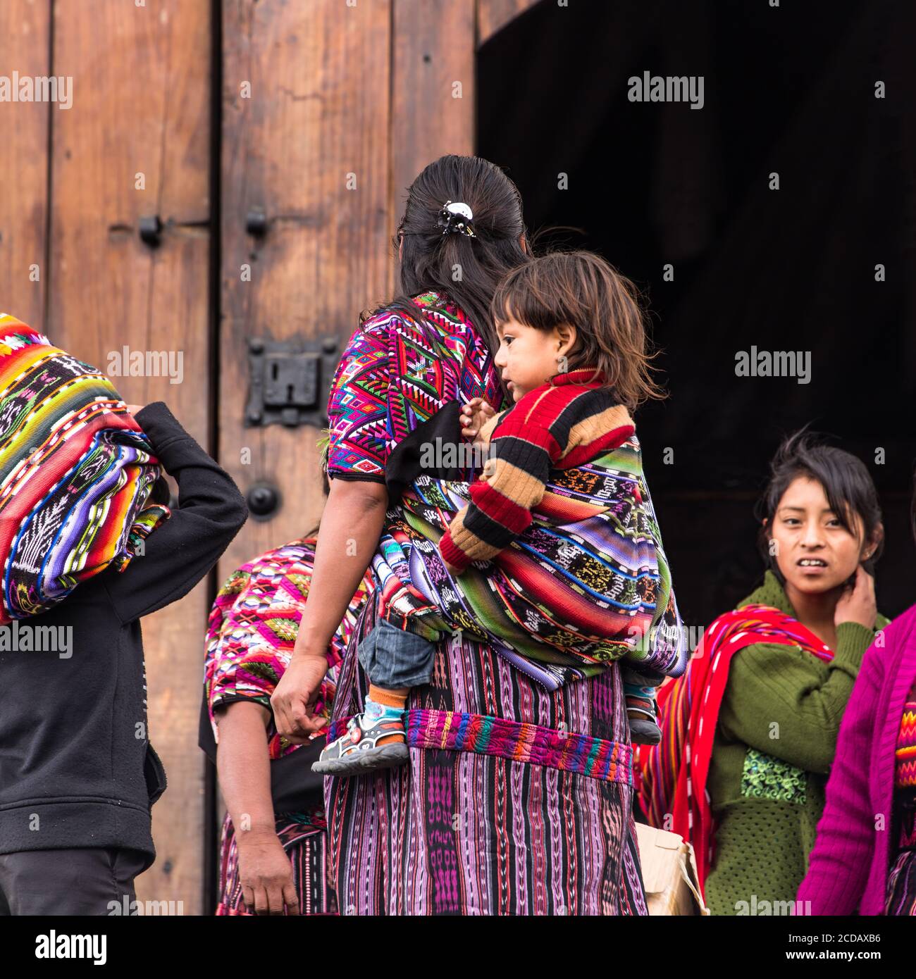 Quiche Mayans in traditional dress in front of the old wooden doorway ...