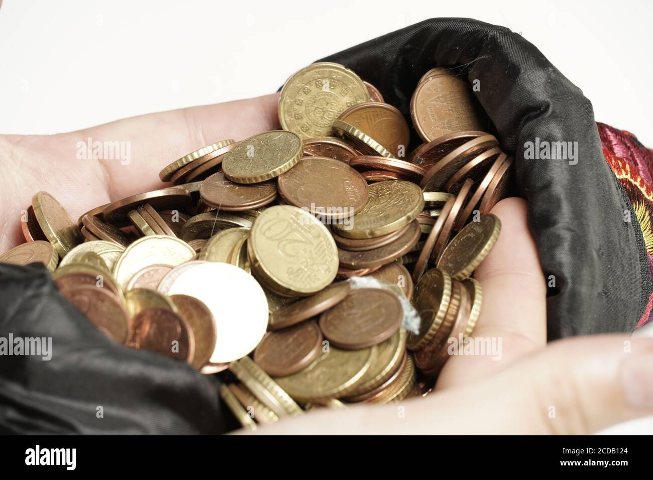 close up view of man's hands grabbing many coins on a white background ...