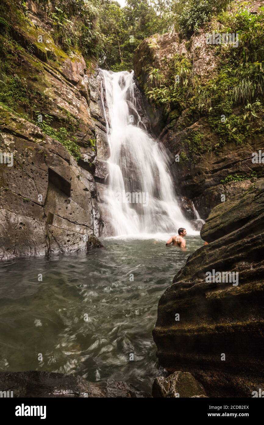 A tourist swims in the pool below La Mina Falls or Cascada la Mina in ...