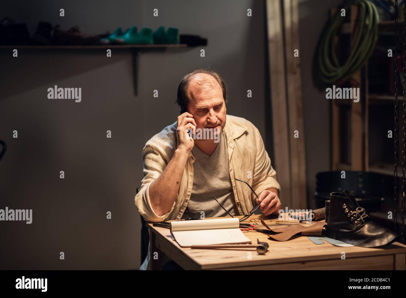 an old shoemaker makes shoes out of leather and answers questions from ...