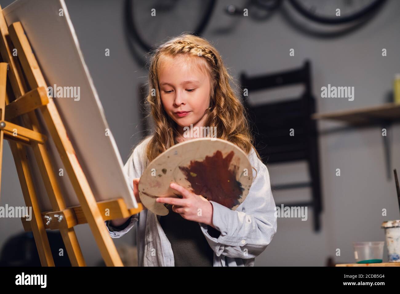 An art school student mixes colors on a palette for her canvas drawing ...