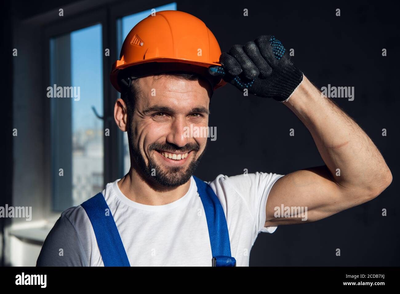Engineer in blue overalls and white shirt holds his helmet with his ...