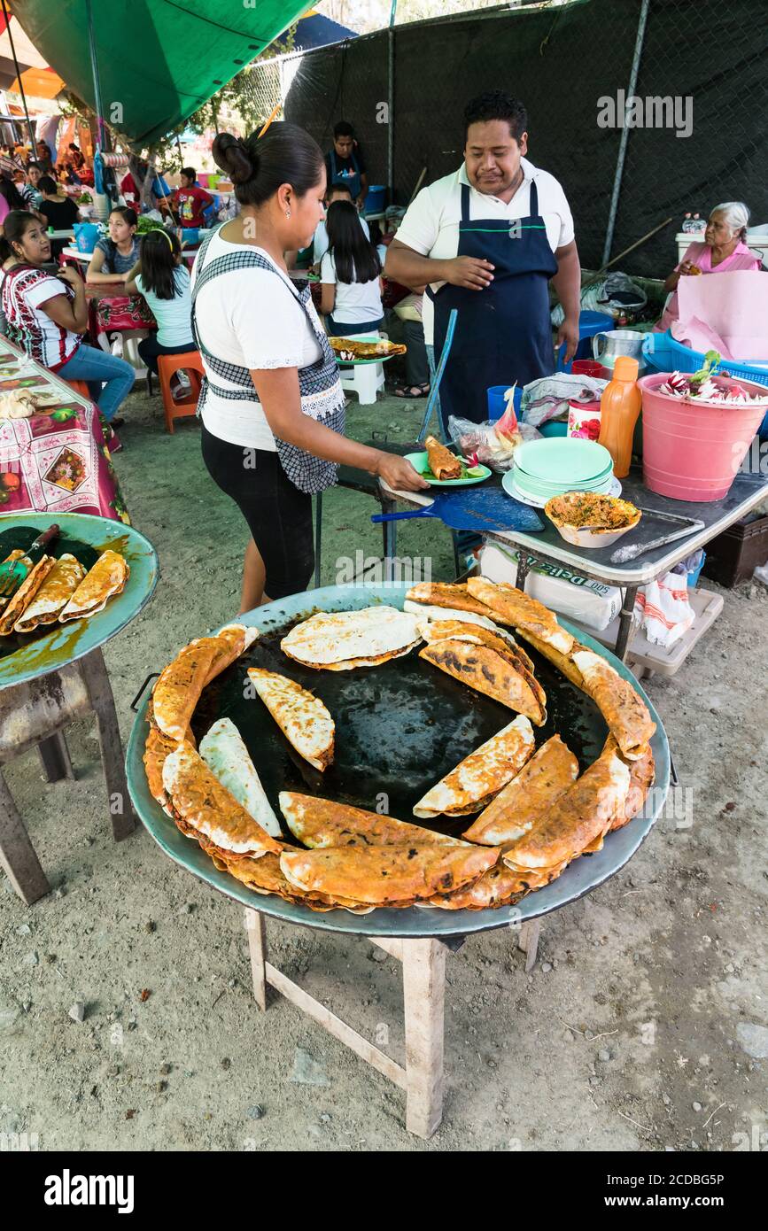 Yellow mole and pork empenadas grilling on a metal comal over a wood ...