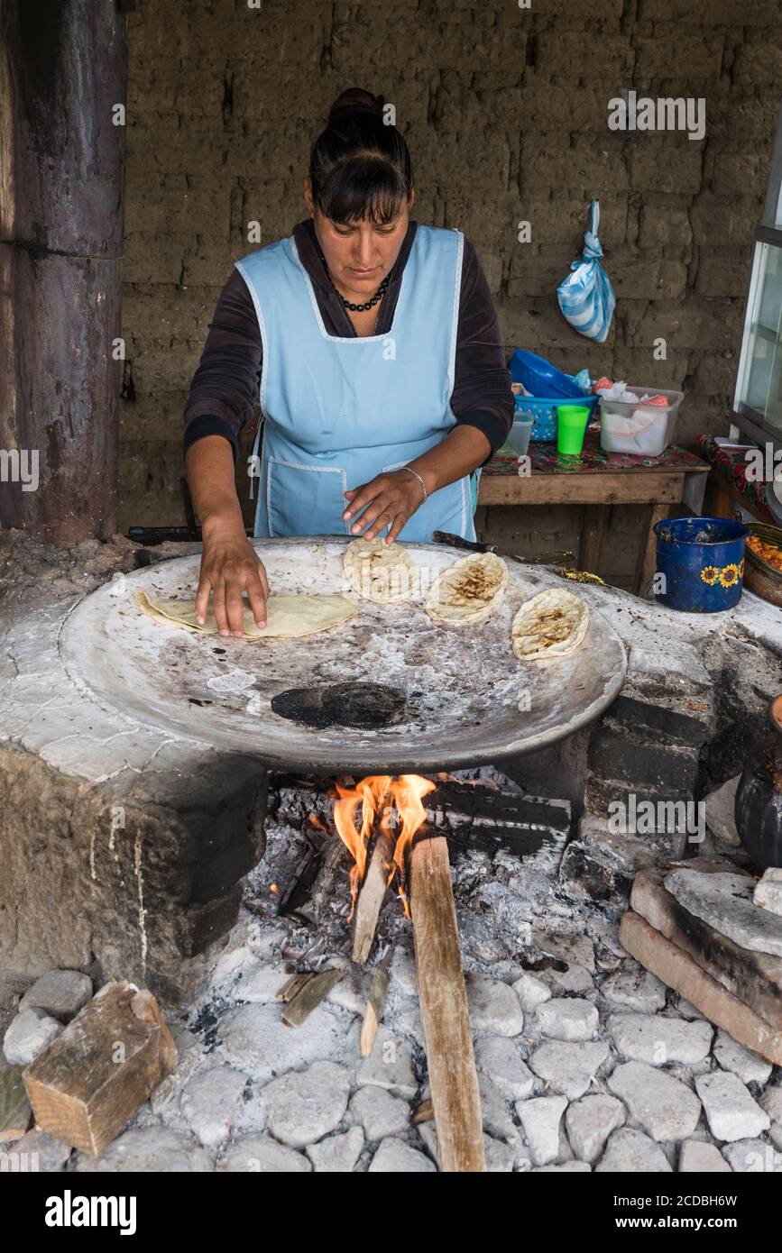 A cook at a roadside restaurant makes memelas or memelitas on a comal ...