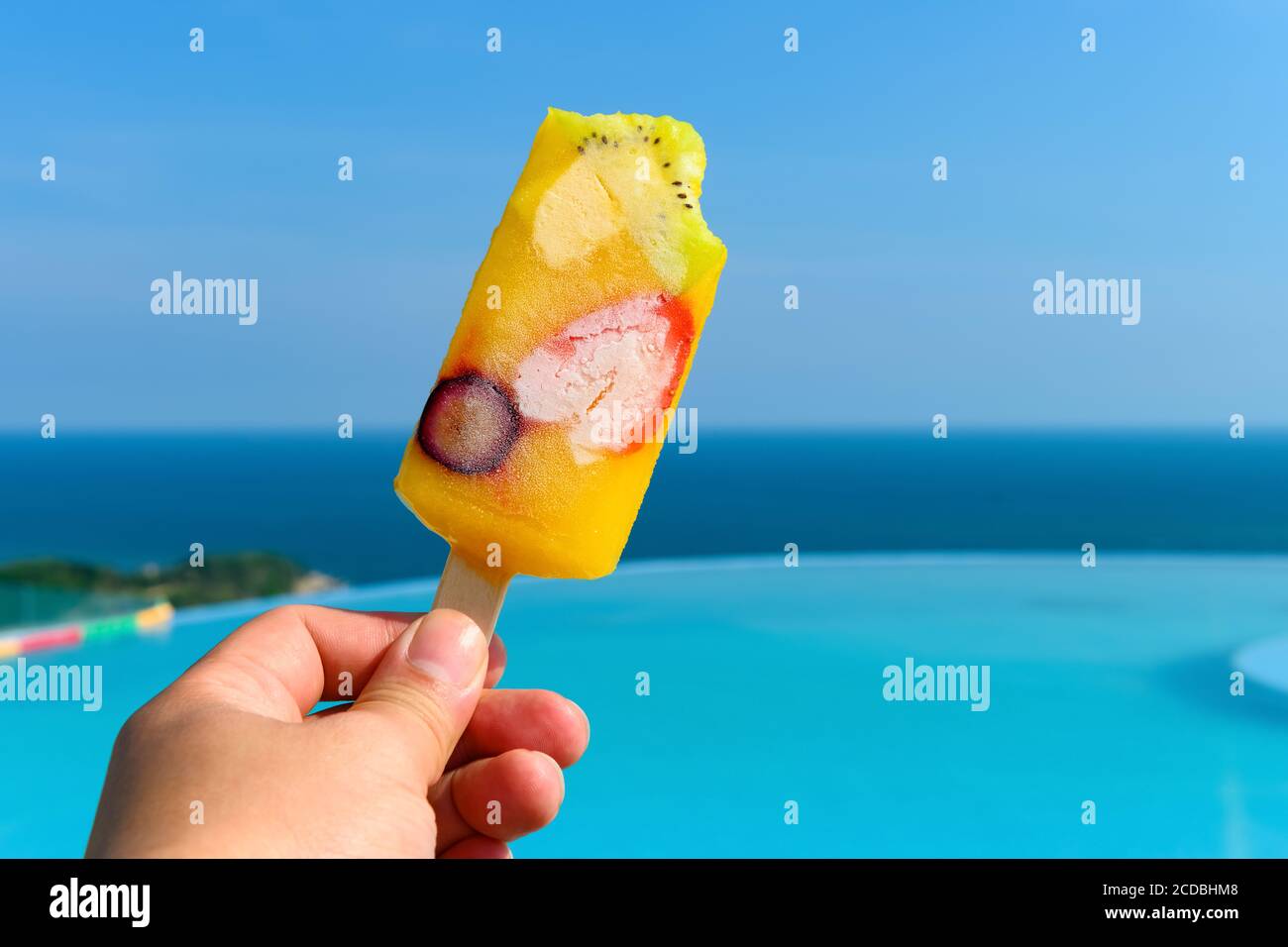 eating a fresh fruit popsicle in front of a swimming pool with the ...