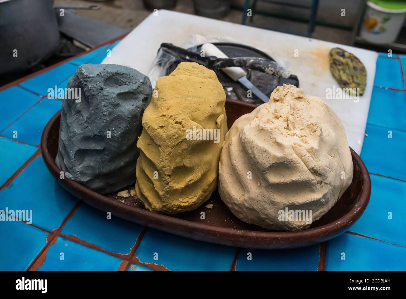 Tortilla dough made from blue, yellow, and white corn masa. Behind is a ...