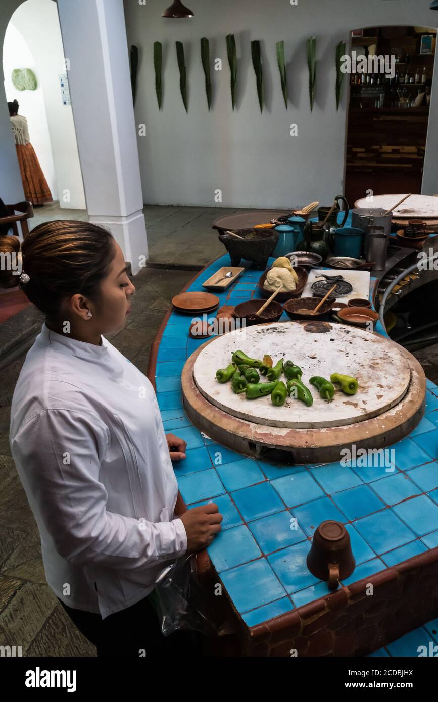 A waitress roasts hot chile peppers on a comal in a restaurant in ...