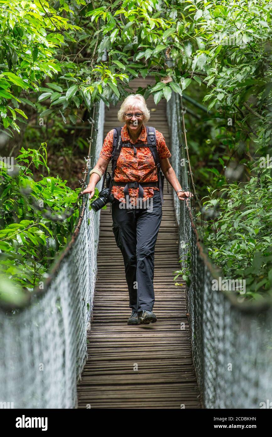 A tourist crosses a swinging bridge in the rainforest of the Atitlan ...